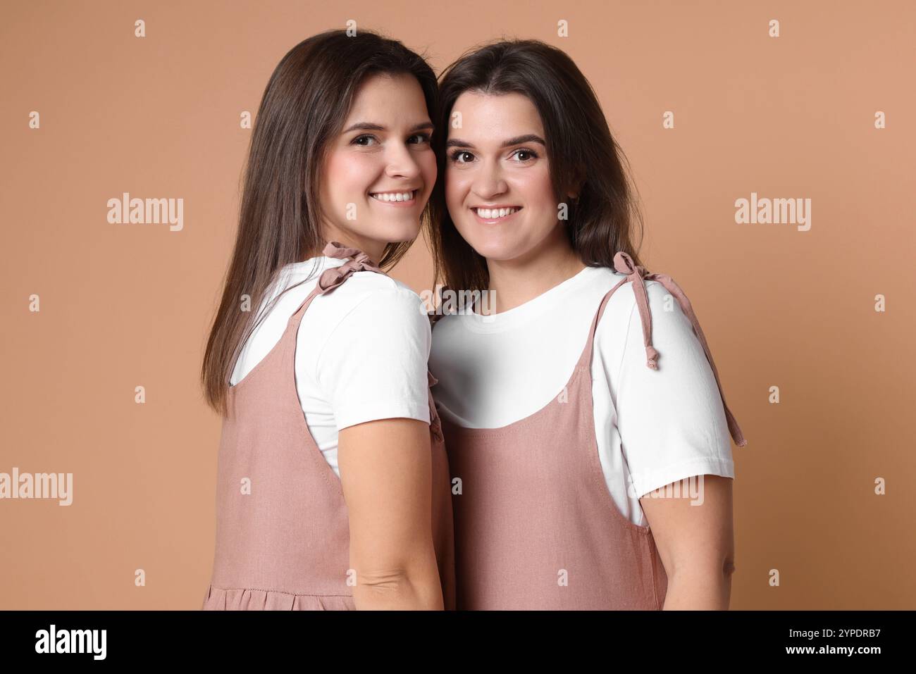 Portrait of happy twin sisters on pale brown background Stock Photo - Alamy