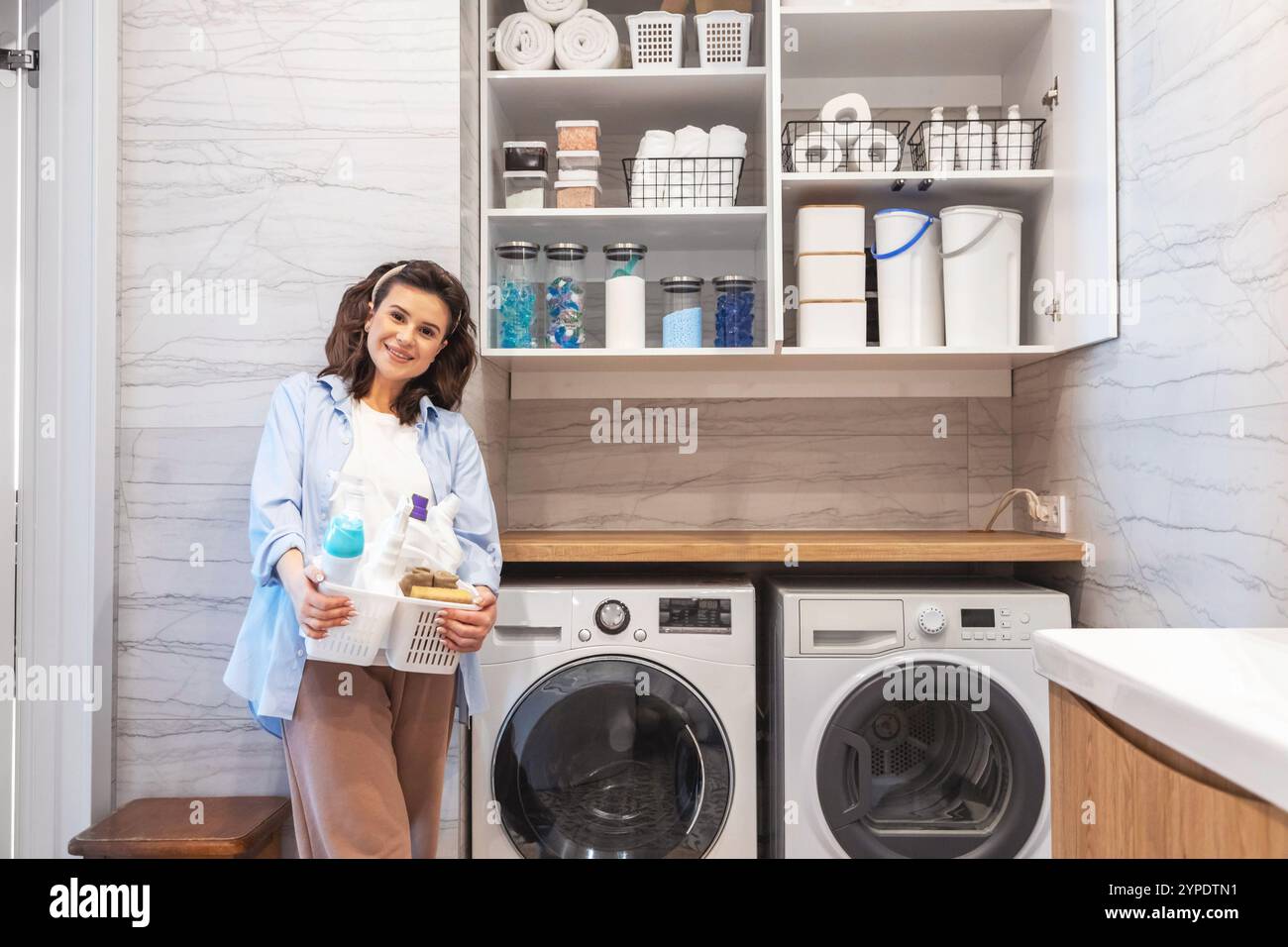 Woman housewife posing at modern white wooden bathroom laundry storage ...