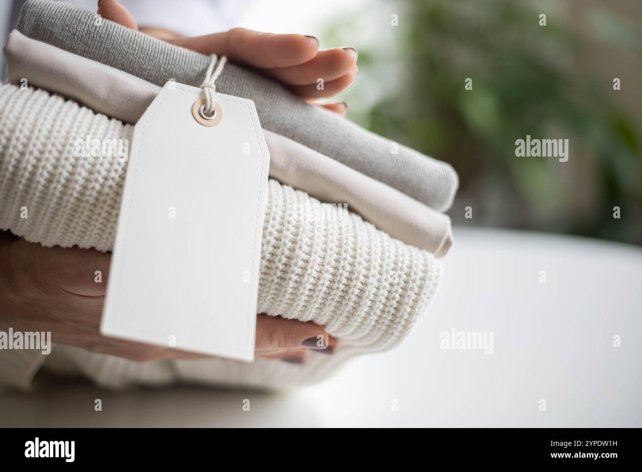 Women's hands hold a stack of neat, clean, cotton clothes in neutral ...