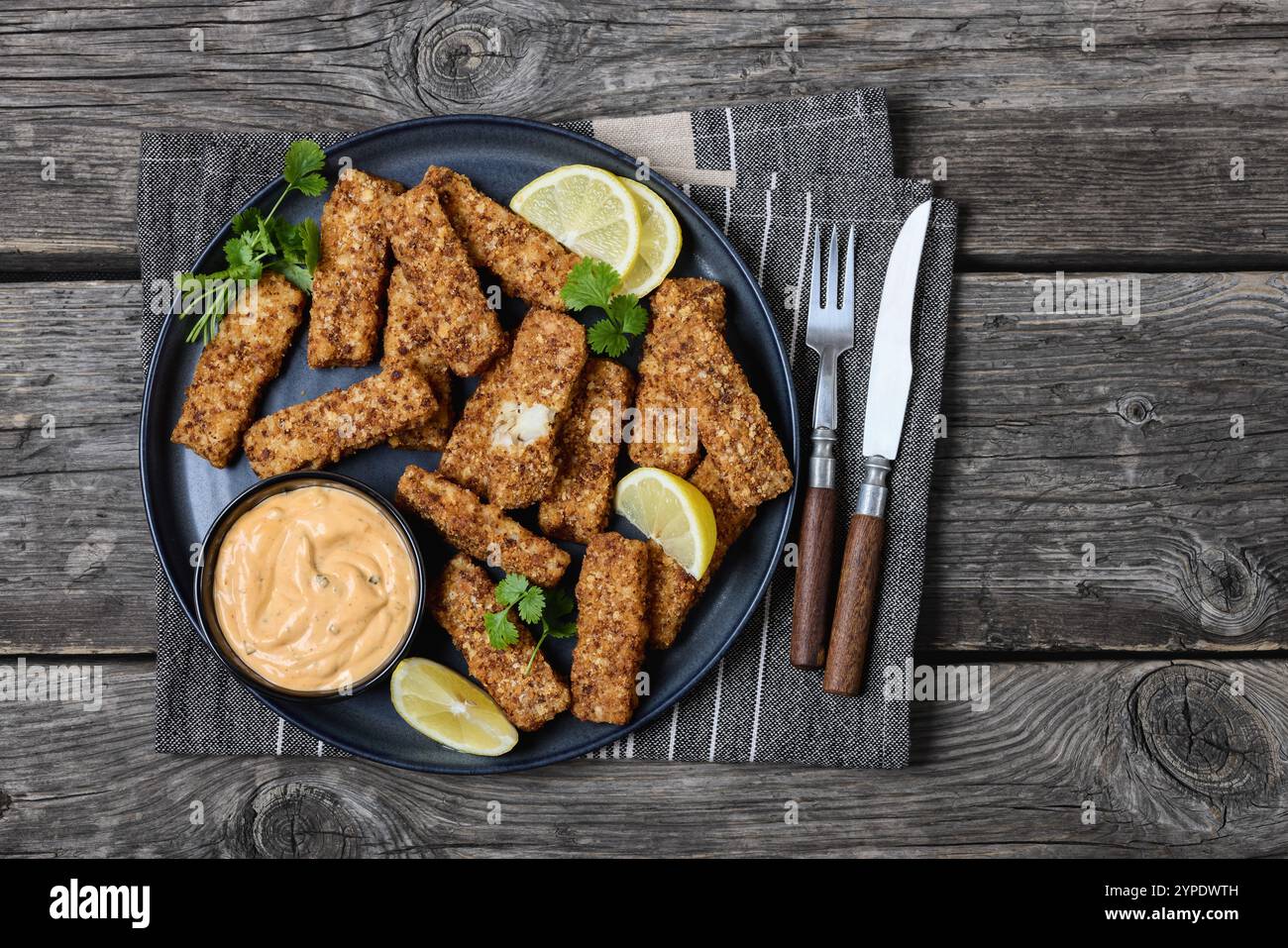pretzel crusted fish sticks with lemon slices and paprika mayo sauce on ...