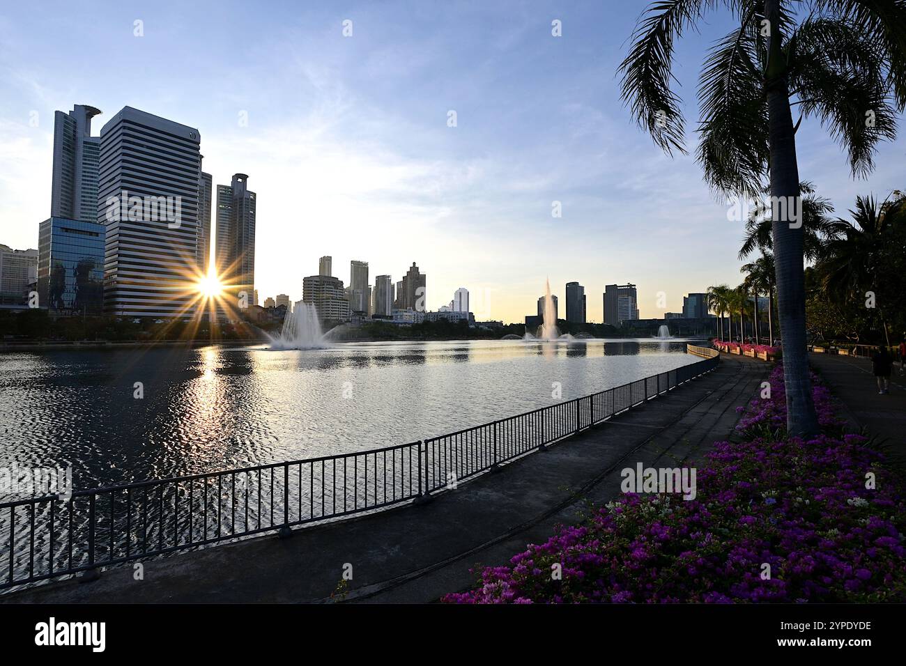 The rising sun peeking through buildings along Ratchadaphisek Road with ...