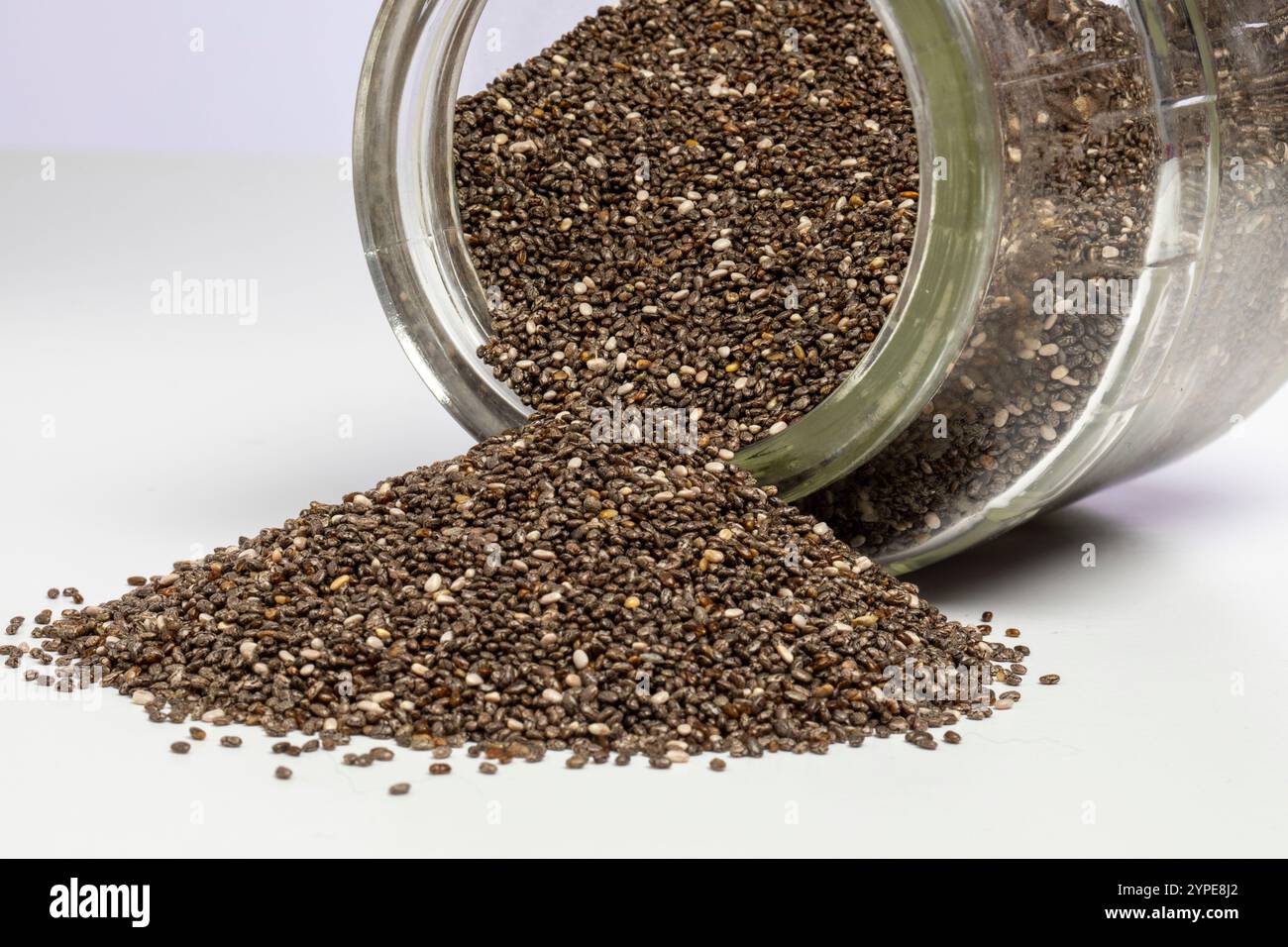 Chia seeds pouring out of a glass container Stock Photo - Alamy