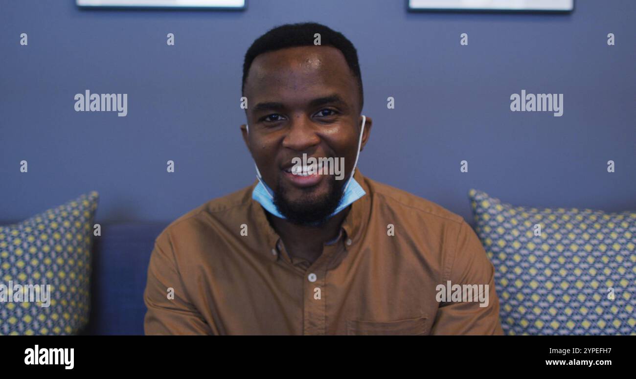 Portrait of african american man face mask around his neck talking and ...
