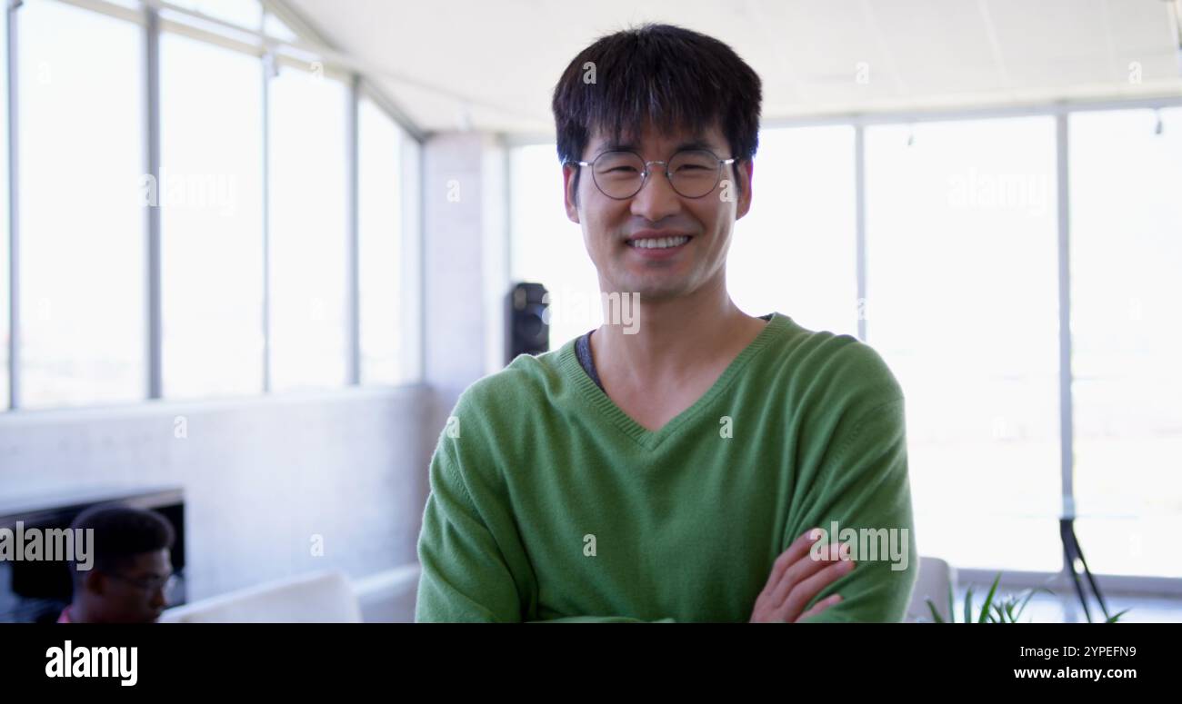 Front view of young handsome Asian male executive standing with arms ...