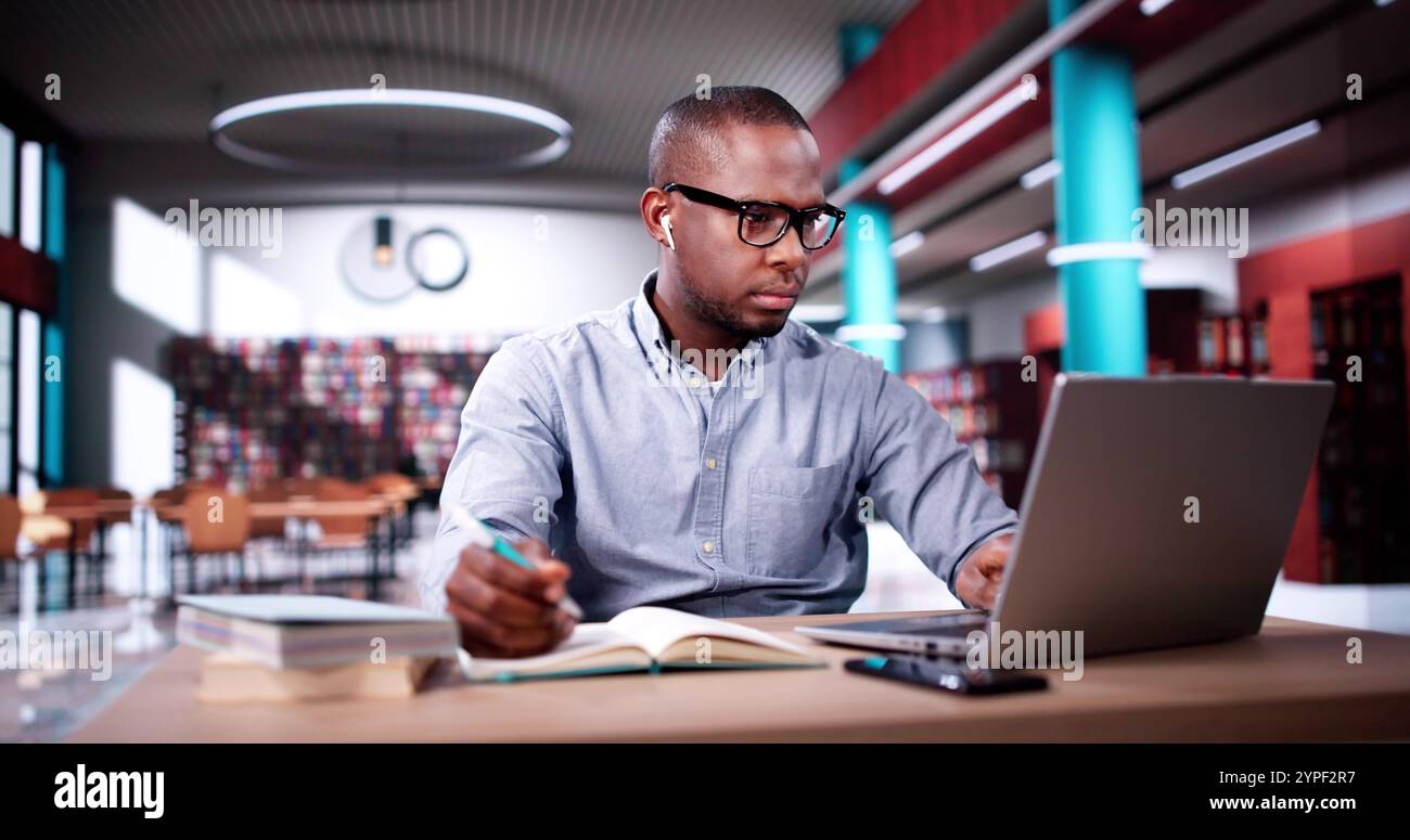 Male Student Studying With Computer Doing Research At Library Stock ...