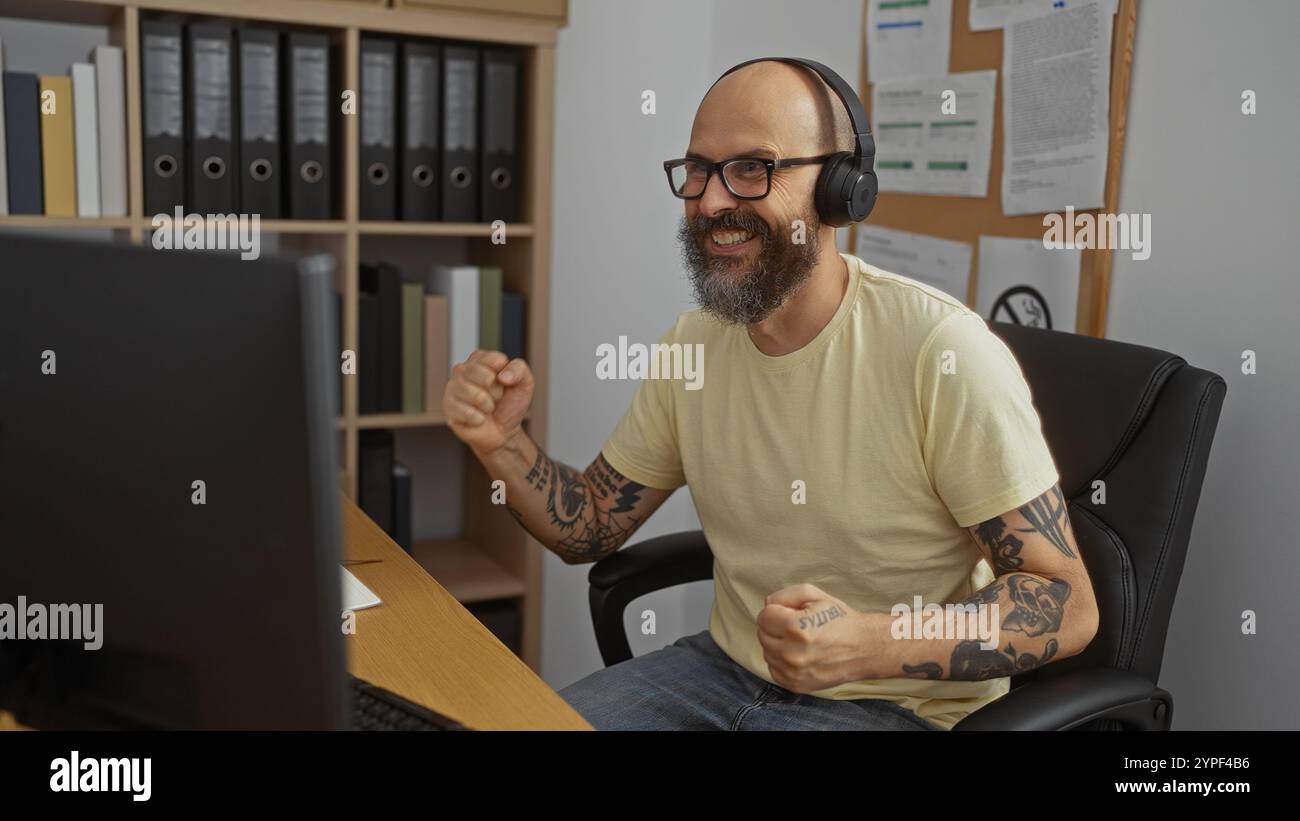 Hispanic man with tattoos and beard celebrating at his desk in an ...