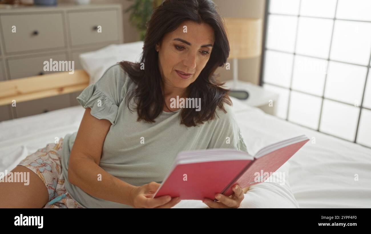 Mature woman reading a book in a cozy bedroom setting, her relaxed ...