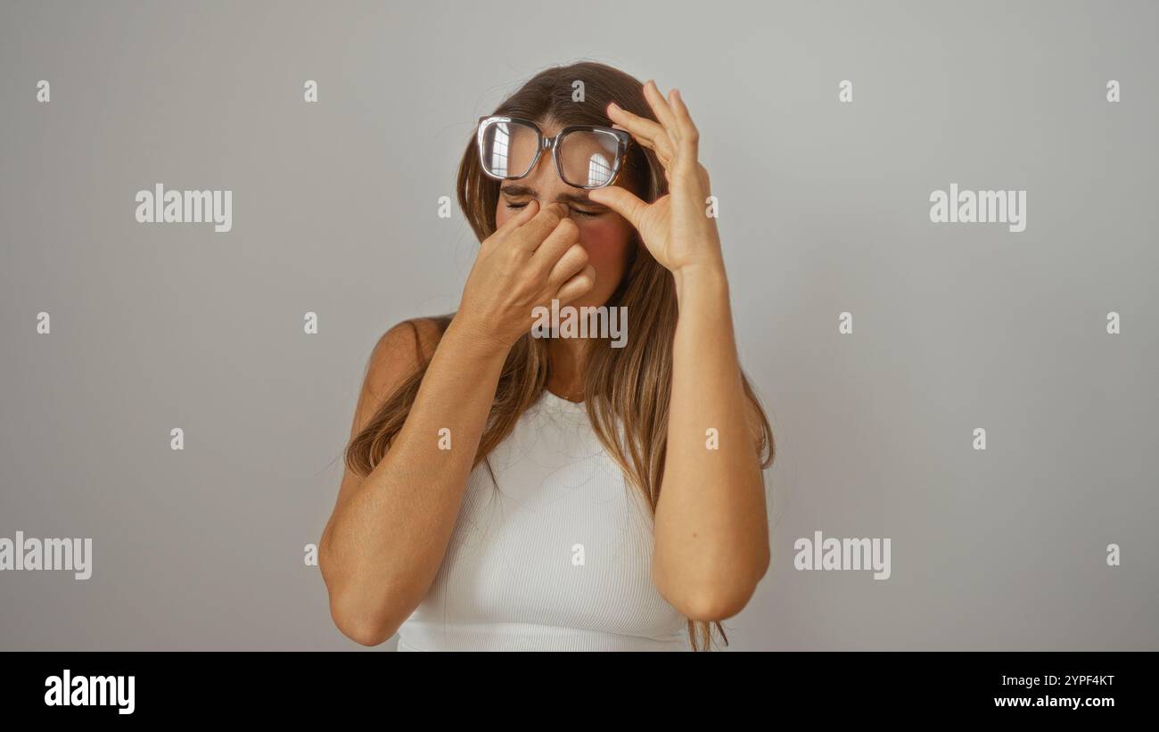 Hispanic woman frowning while removing her glasses and rubbing her eyes ...