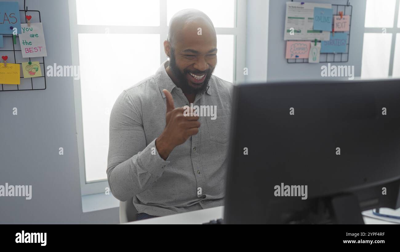 Bald african american man giving a thumbs up while working on the ...