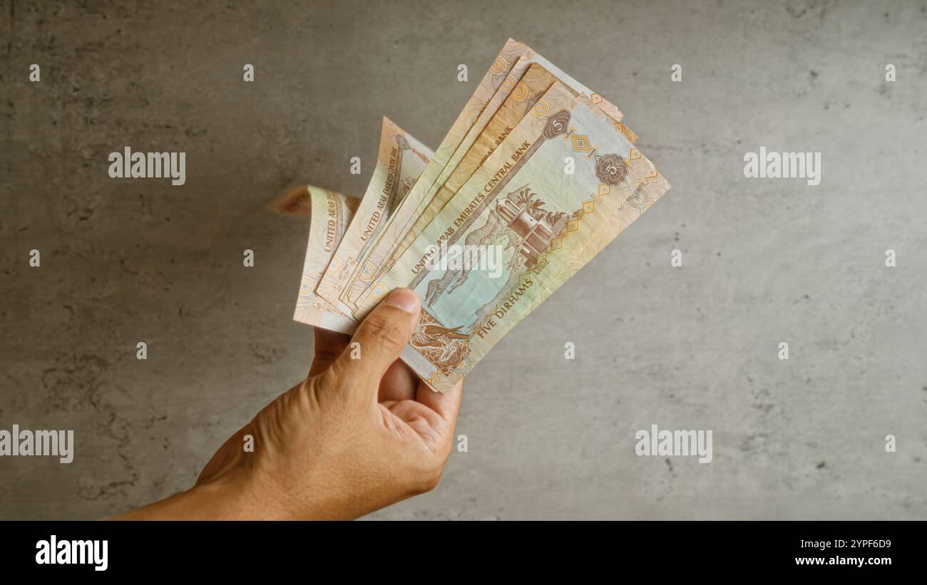 Hand holding several united arab emirates dirham banknotes against a ...