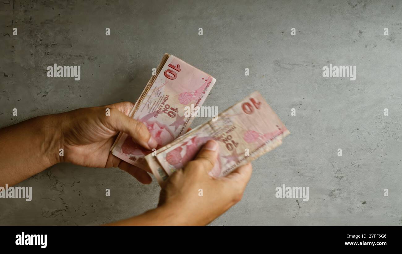 Hands holding turkish lira bills on a concrete background, depicting a ...