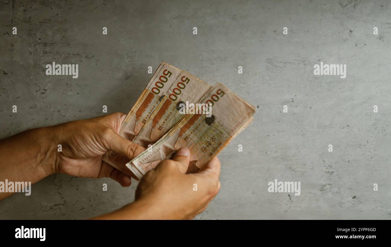 Hands holding and counting korean won cash against a concrete ...