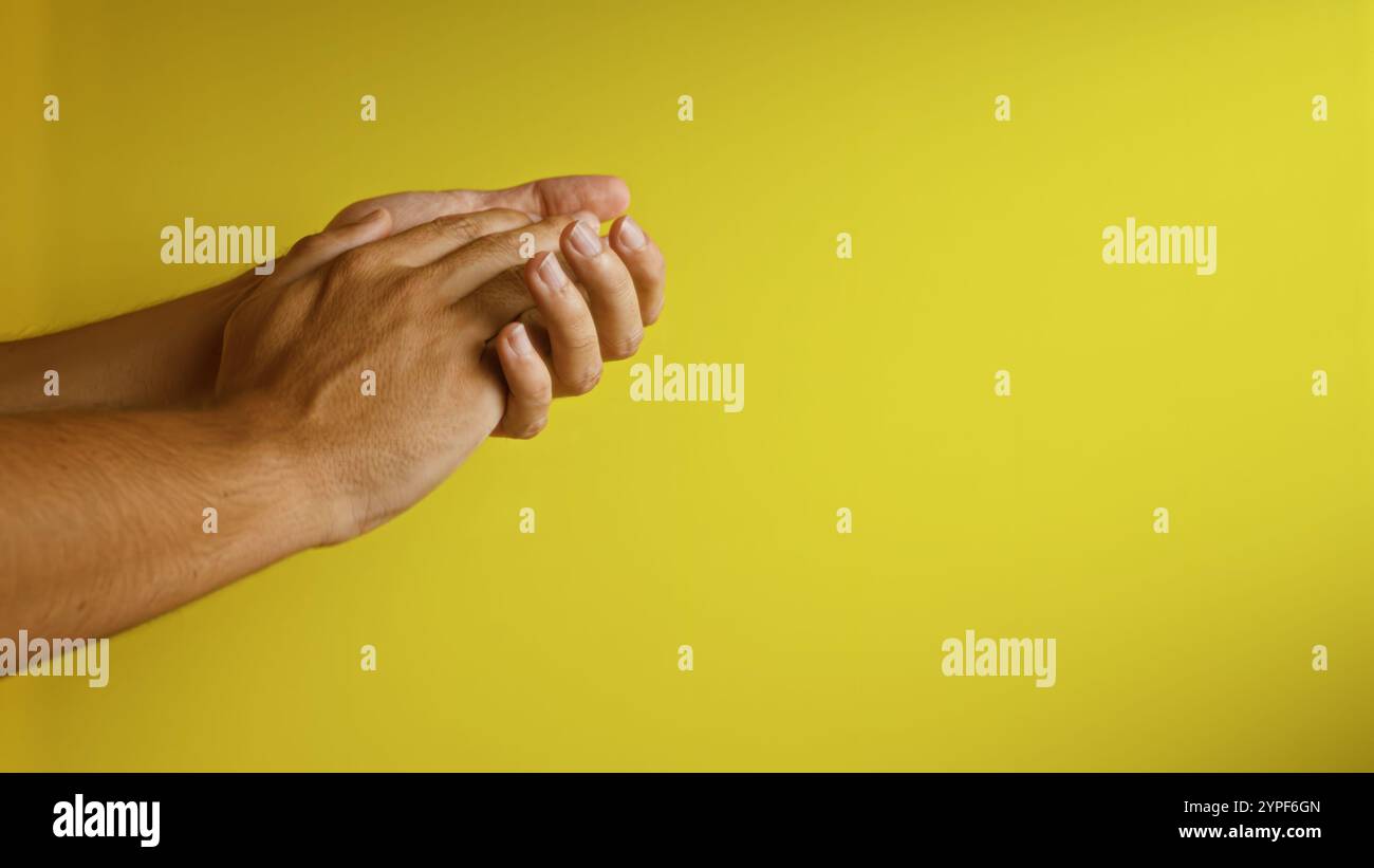 Man showing hands with clasped fingers against yellow background Stock ...