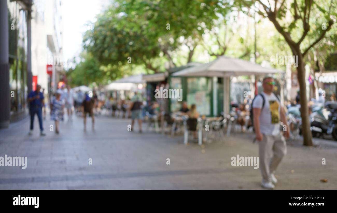 Blurred crowd walking through an outdoor street with defocused ...