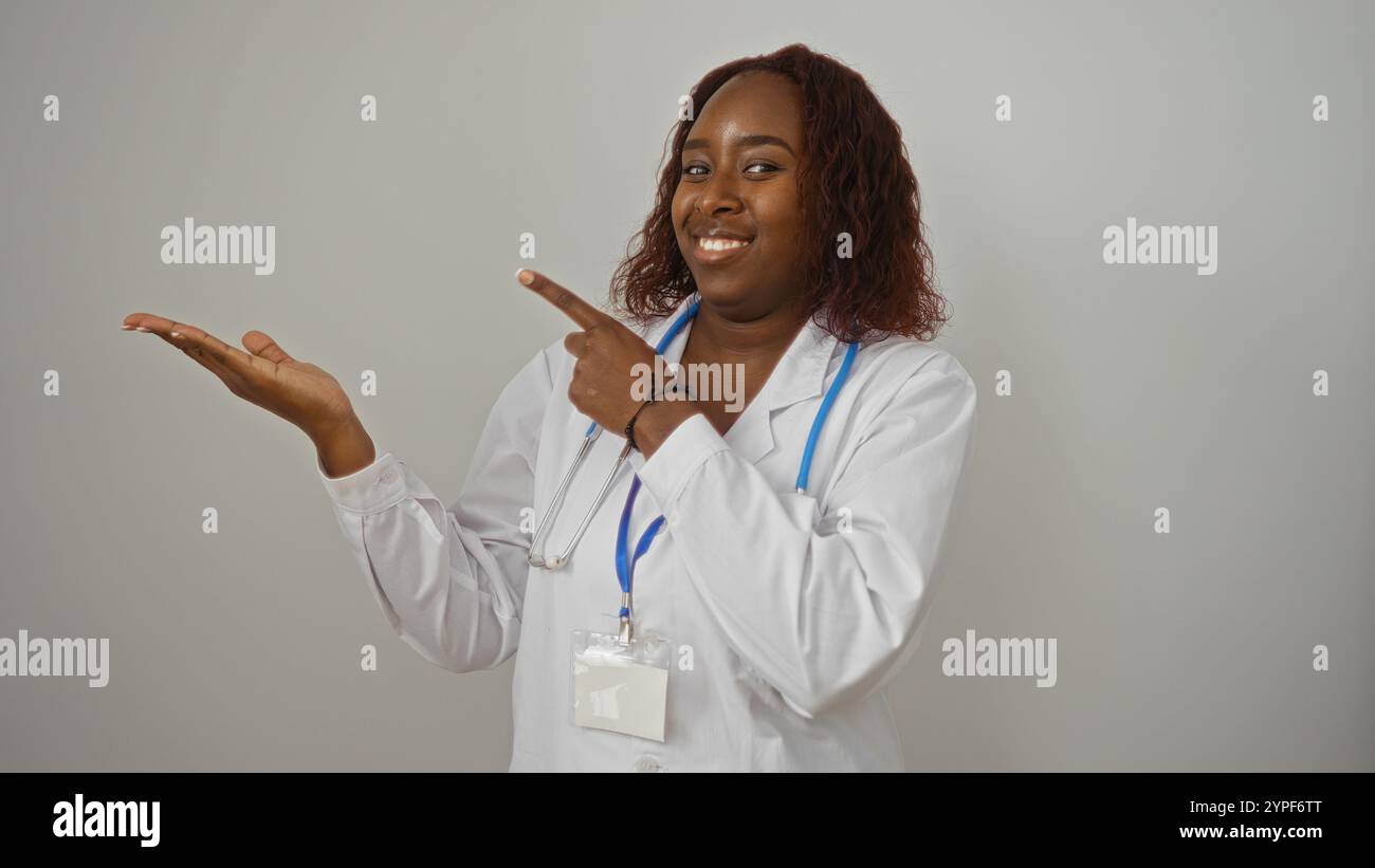 Young african woman doctor smiling and pointing to her hand isolated ...