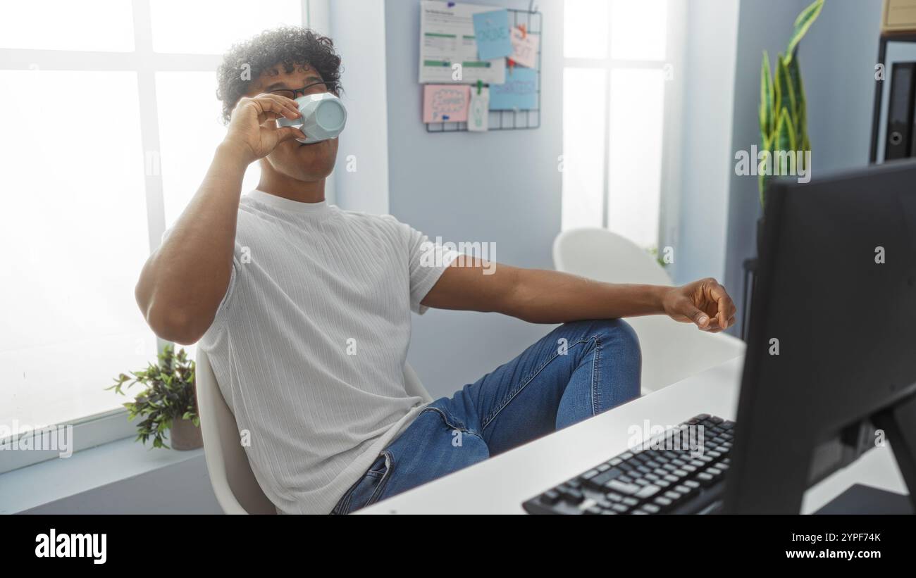 Young man drinking coffee while working in an office, showing a relaxed ...