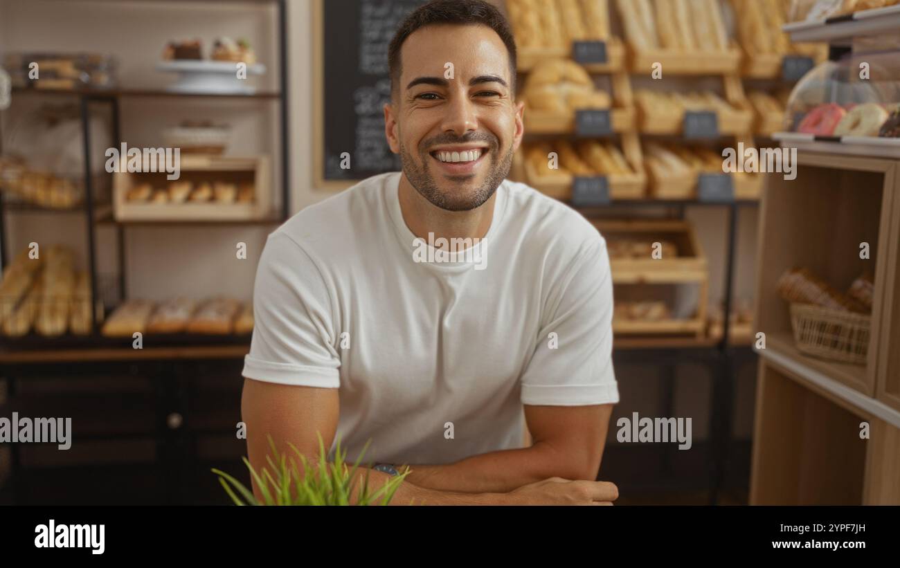 Young man with a beard smiling in a bakery surrounded by displays of ...