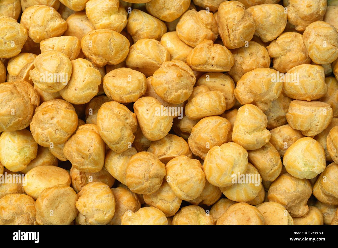 The background is a texture of a large number of profiteroles lying on ...