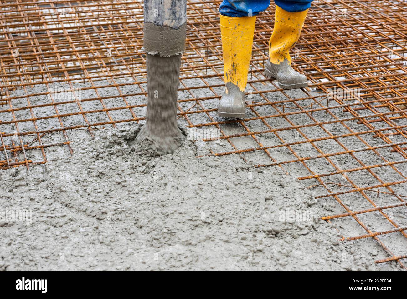 Betonieren von einem Fundament Ein Bauarbeiter betoniert auf Baustahlmatten das Fundament für ...