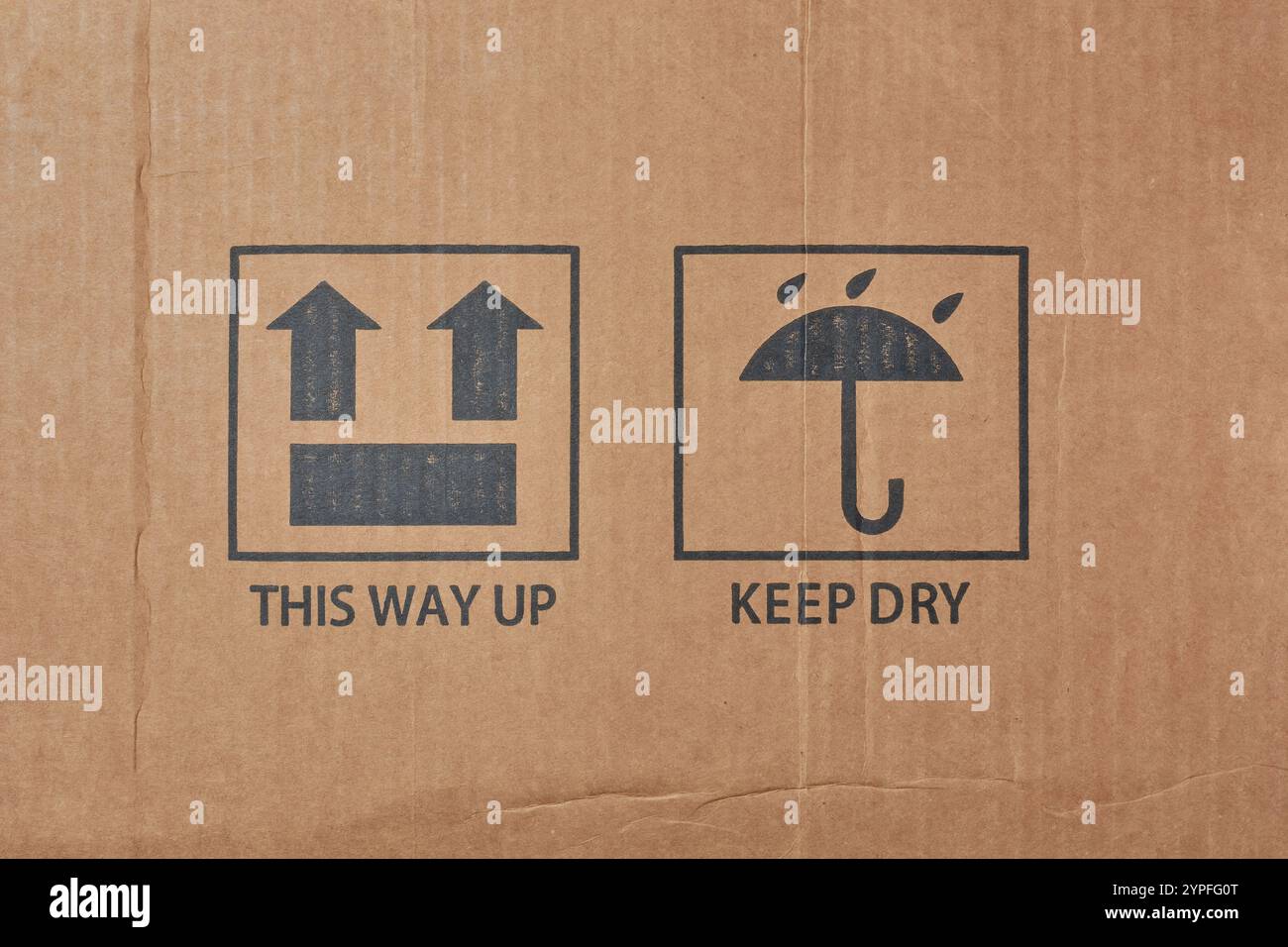 two shipping symbols printed on cardboard box, this way up and keep dry icons with important ...