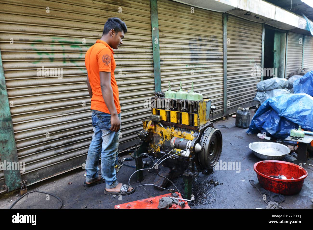 A mechanic fixing an engine at a small workshop in the shipyards area in Dhaka, Bangladesh Stock ...