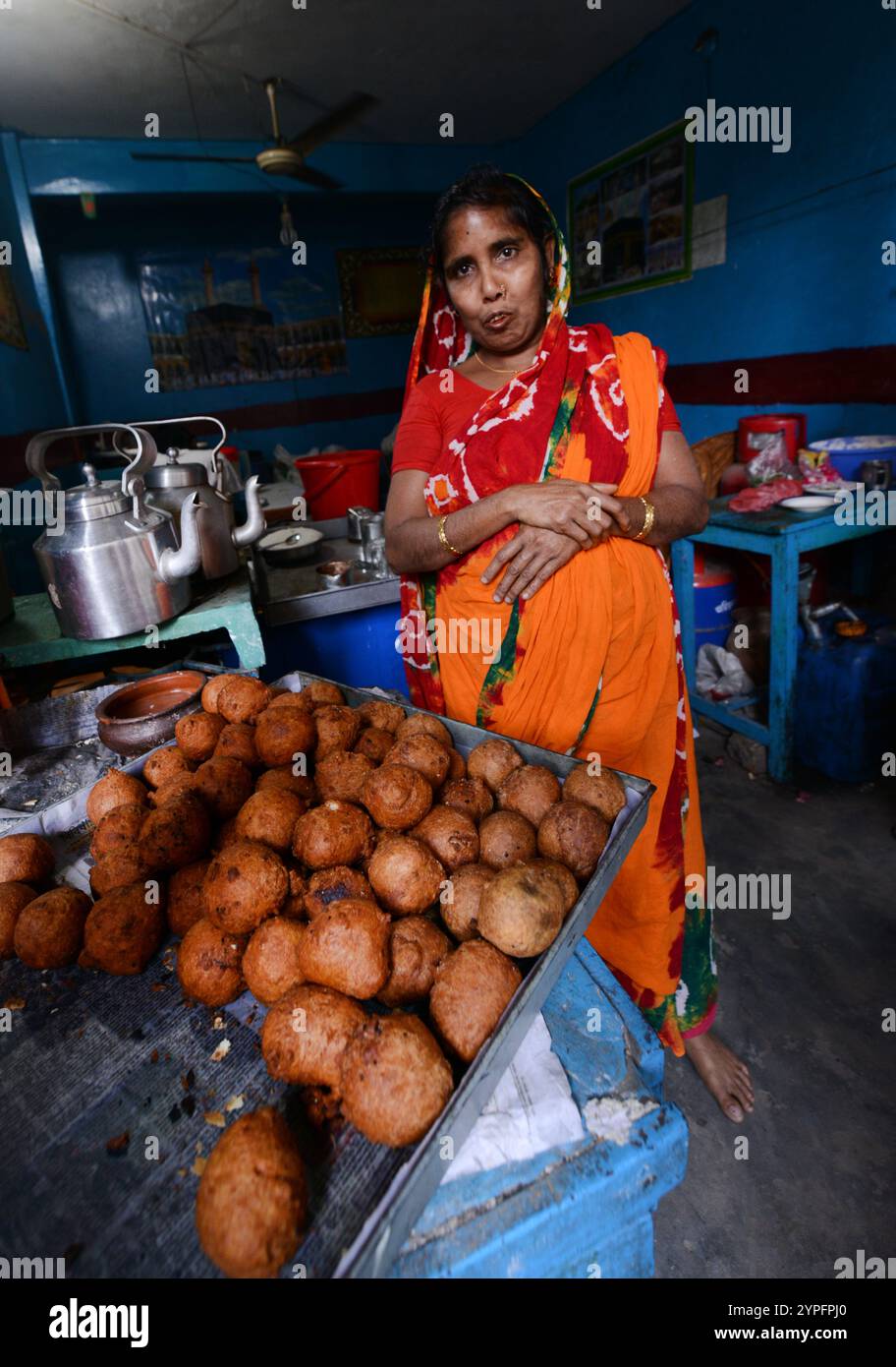 A Bengali woman selling savory snacks in a small tea shop in Dhaka ...