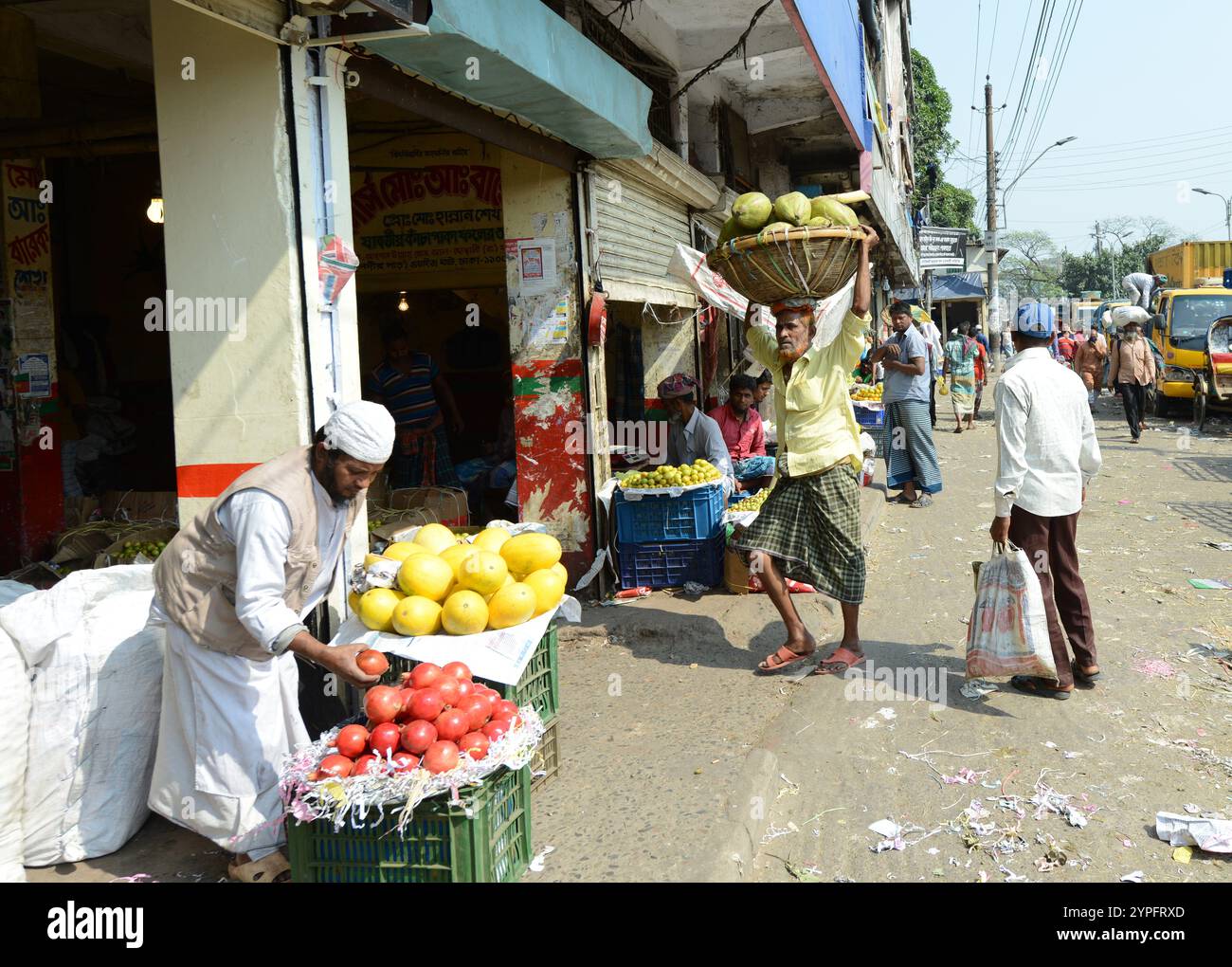 A Bengali man carrying a basket full of coconuts at a local market in the old city of Dhaka ...