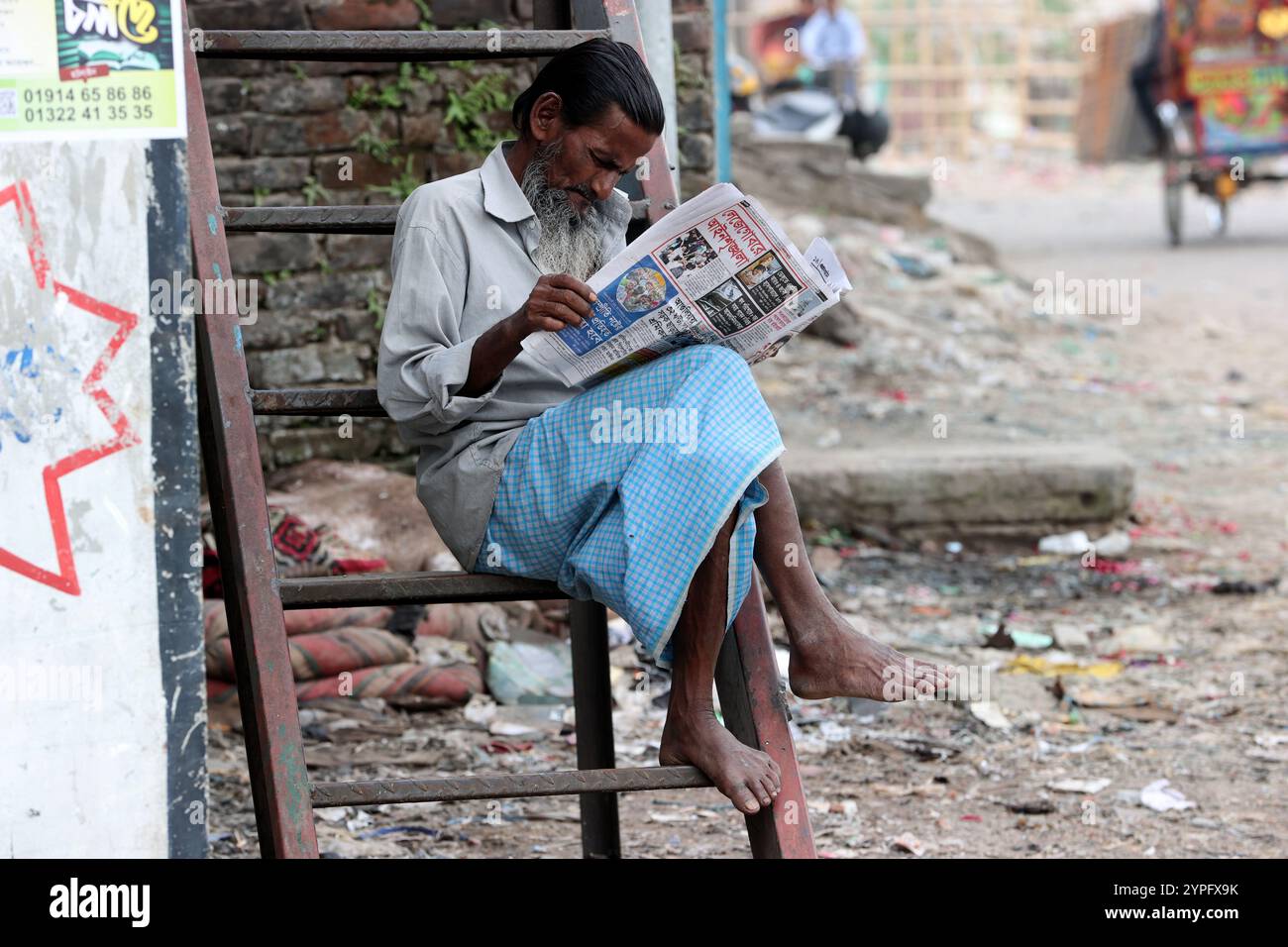 Dhaka, Bangladesh - November 29, 2024: A working man sits reading a ...