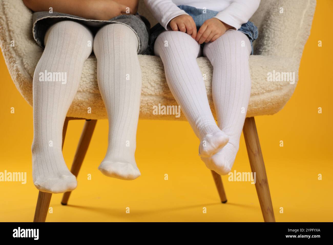 Kids wearing tights in armchair on orange background, closeup Stock ...