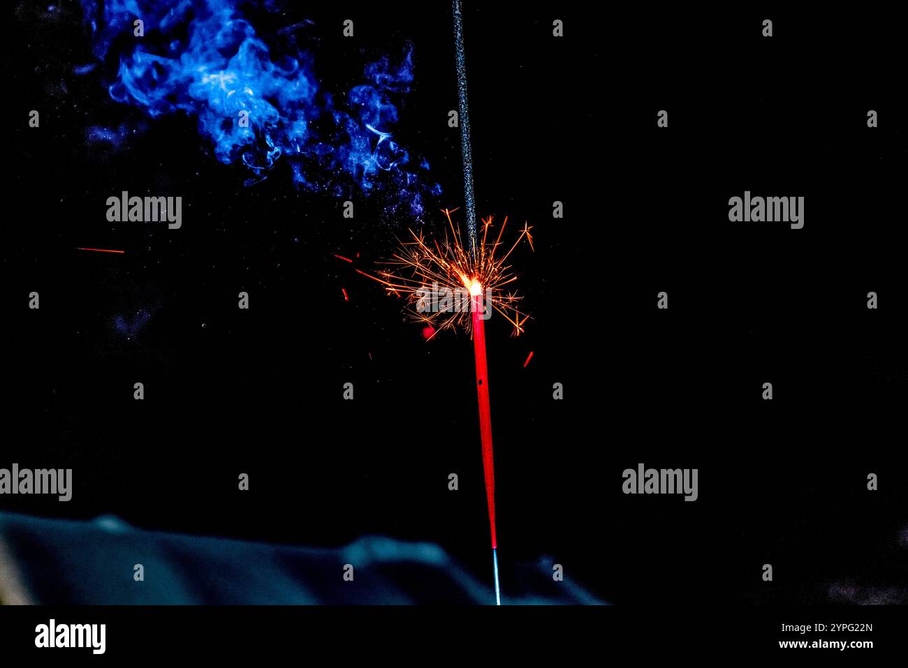 Lit sparkler glowing against black night background with vibrant blue ...