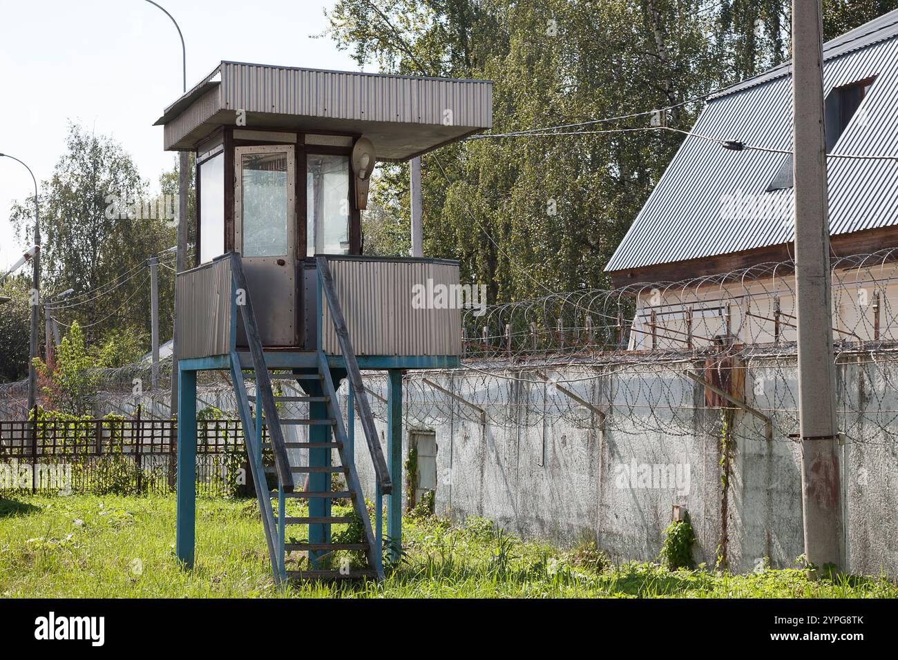 Watch tower and white wall with metal barbed fence in abandoned prison ...