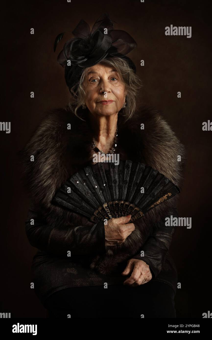 Portrait of an old lady dressed in vintage clothes with a fan on a ...