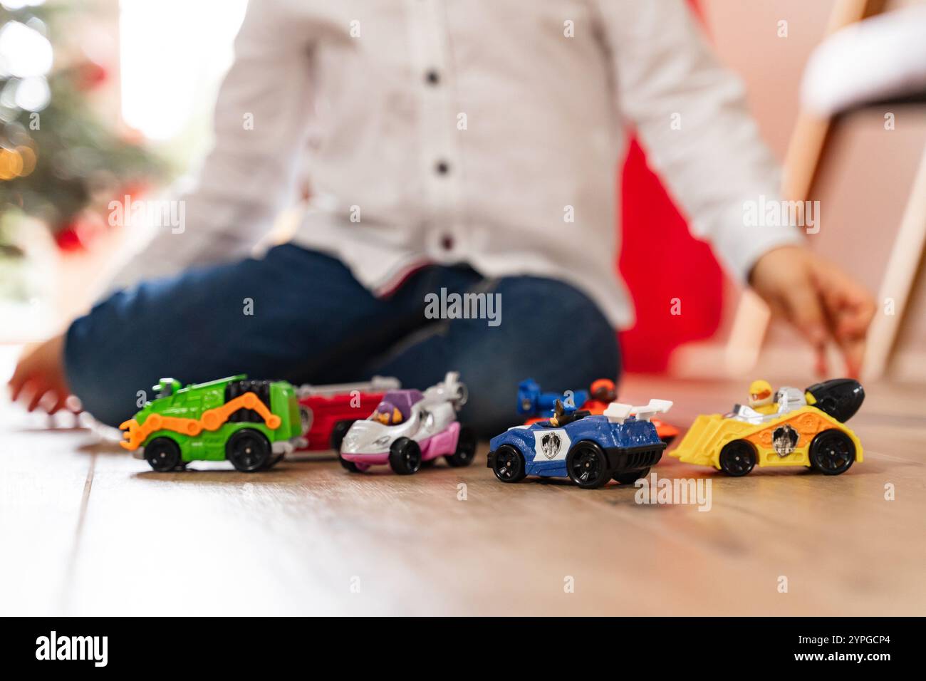 A boy in a white shirt sits on a couch and plays with small cars. Game ...