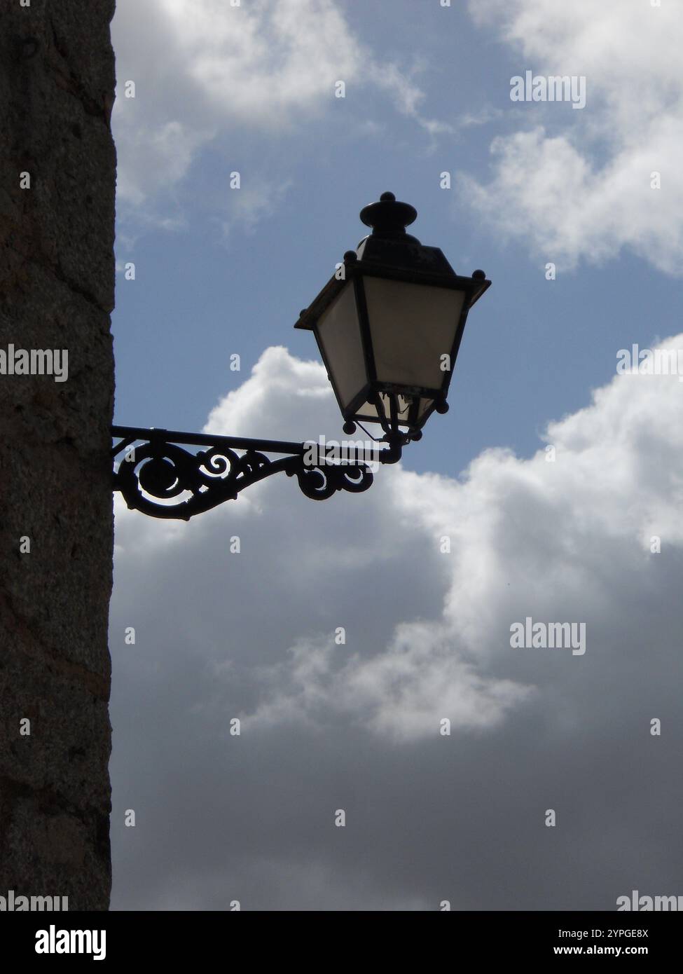 A vintage lantern hangs on a decorative wrought iron bracket. Dark ...