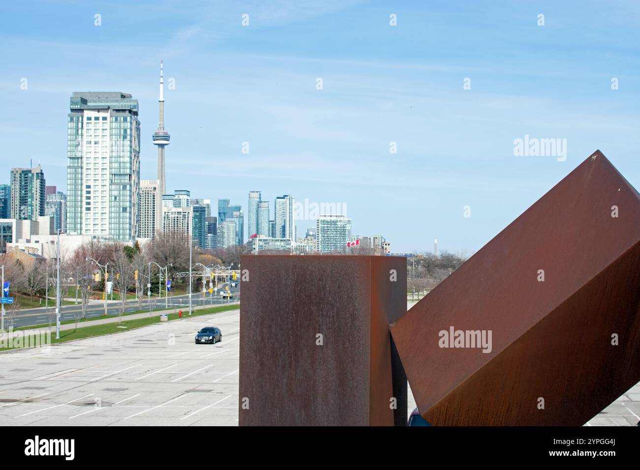 A rusted metal sculpture next to a car park at Ontario Place. CN Tower ...