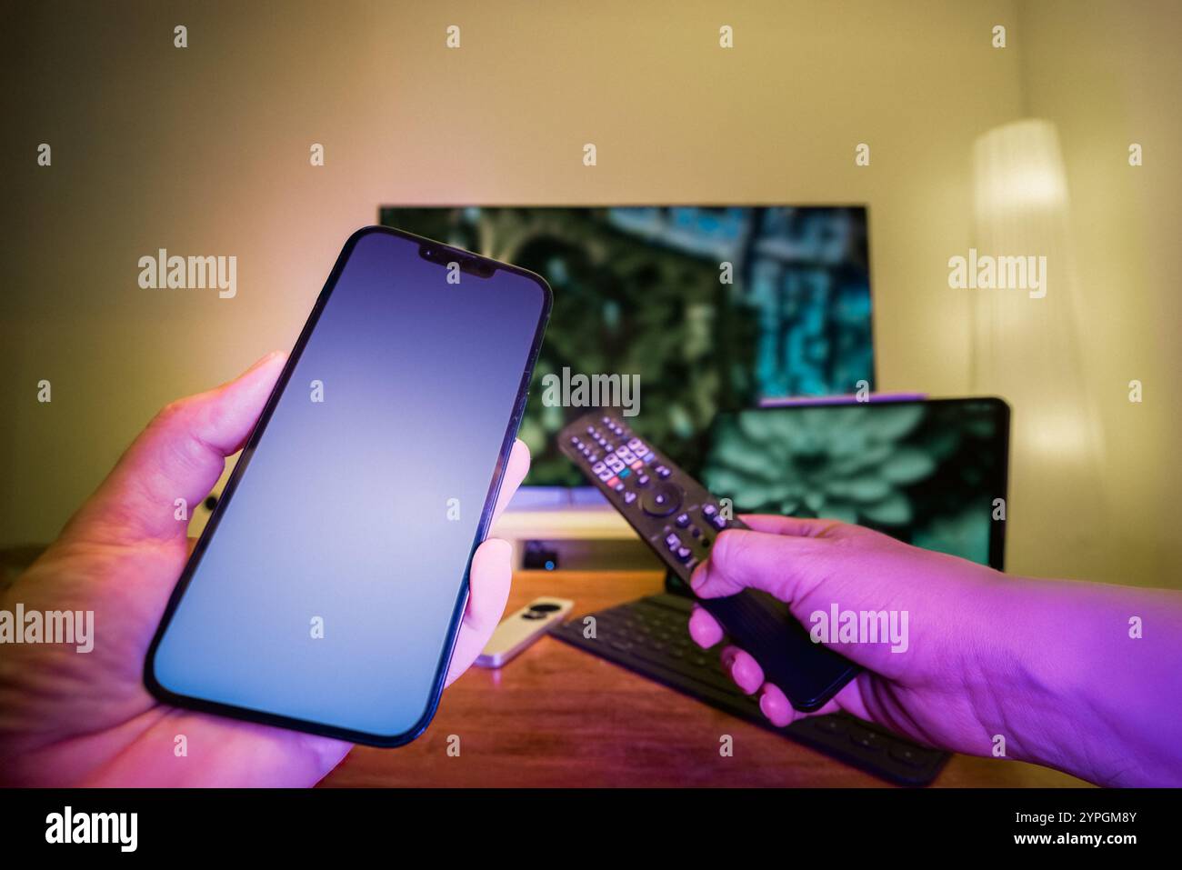 media distraction hand holding smartphone TV remote control laptop ...