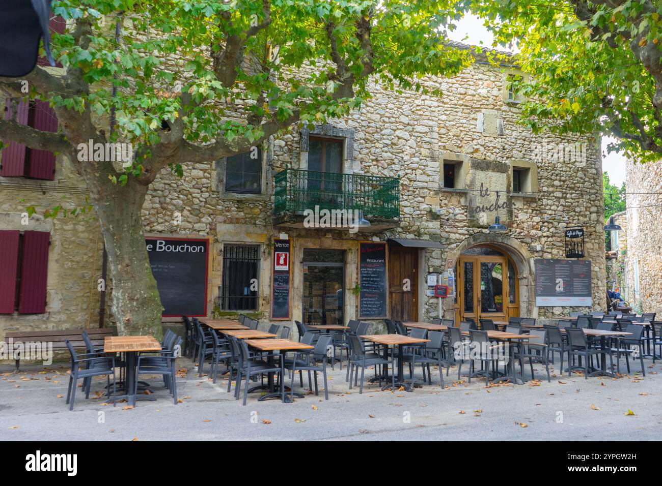 Rustic french cafe with outdoor seating under lush trees in quaint ...