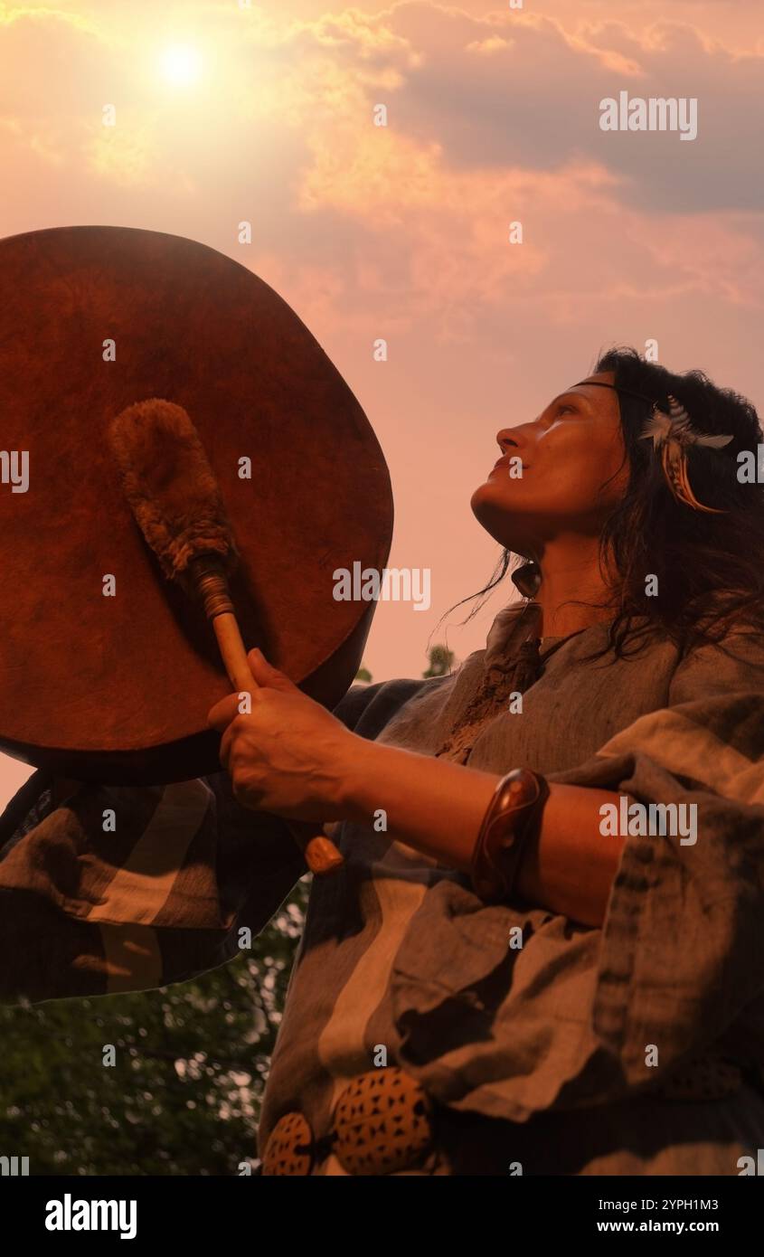 Female shaman performs a ritual with a tambourine at sunset in the ...
