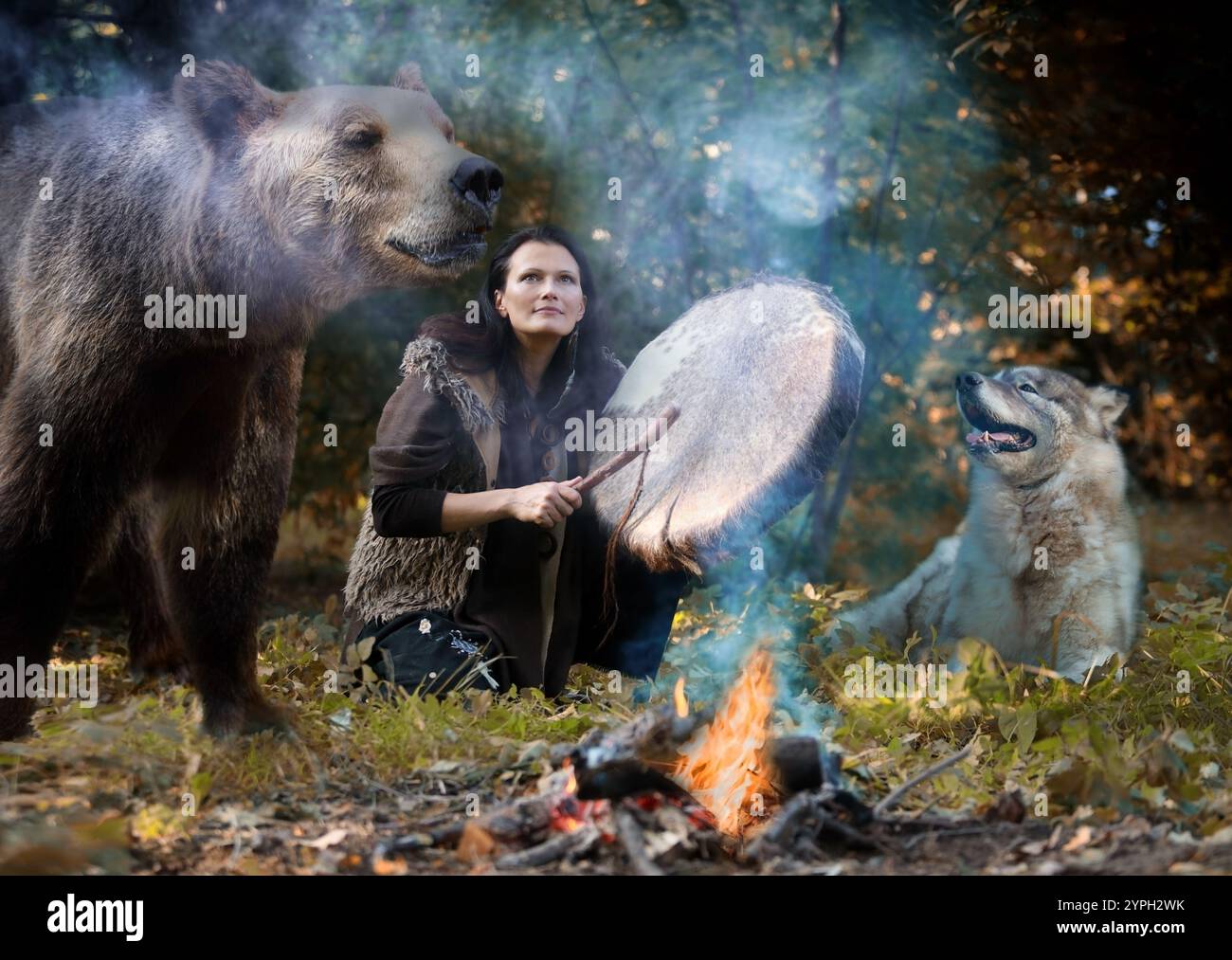 Female shaman playing her shaman sacred drum in the forest among wild ...
