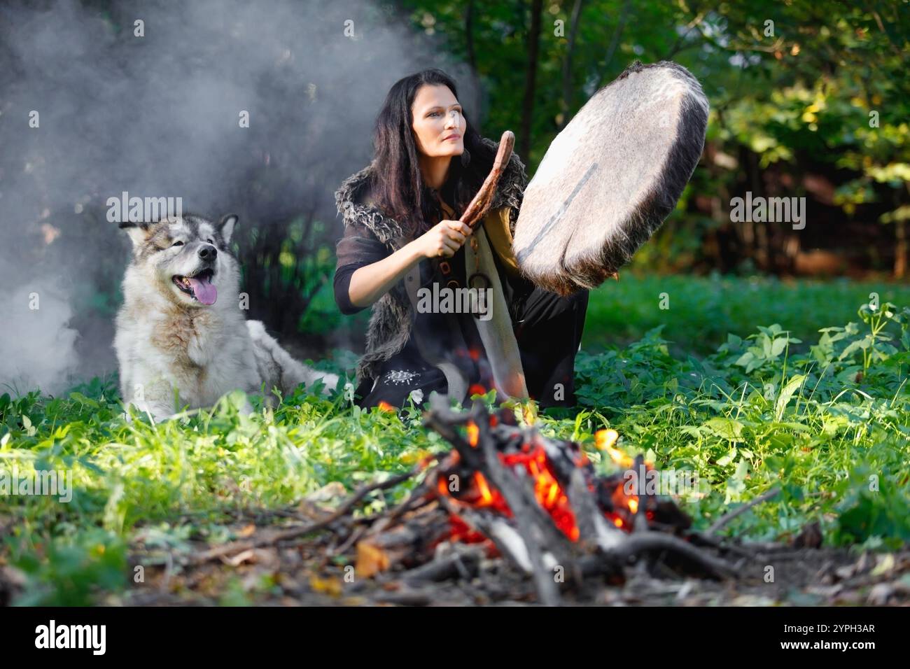 Shaman woman playing her shaman sacred drum in the evening forest by ...