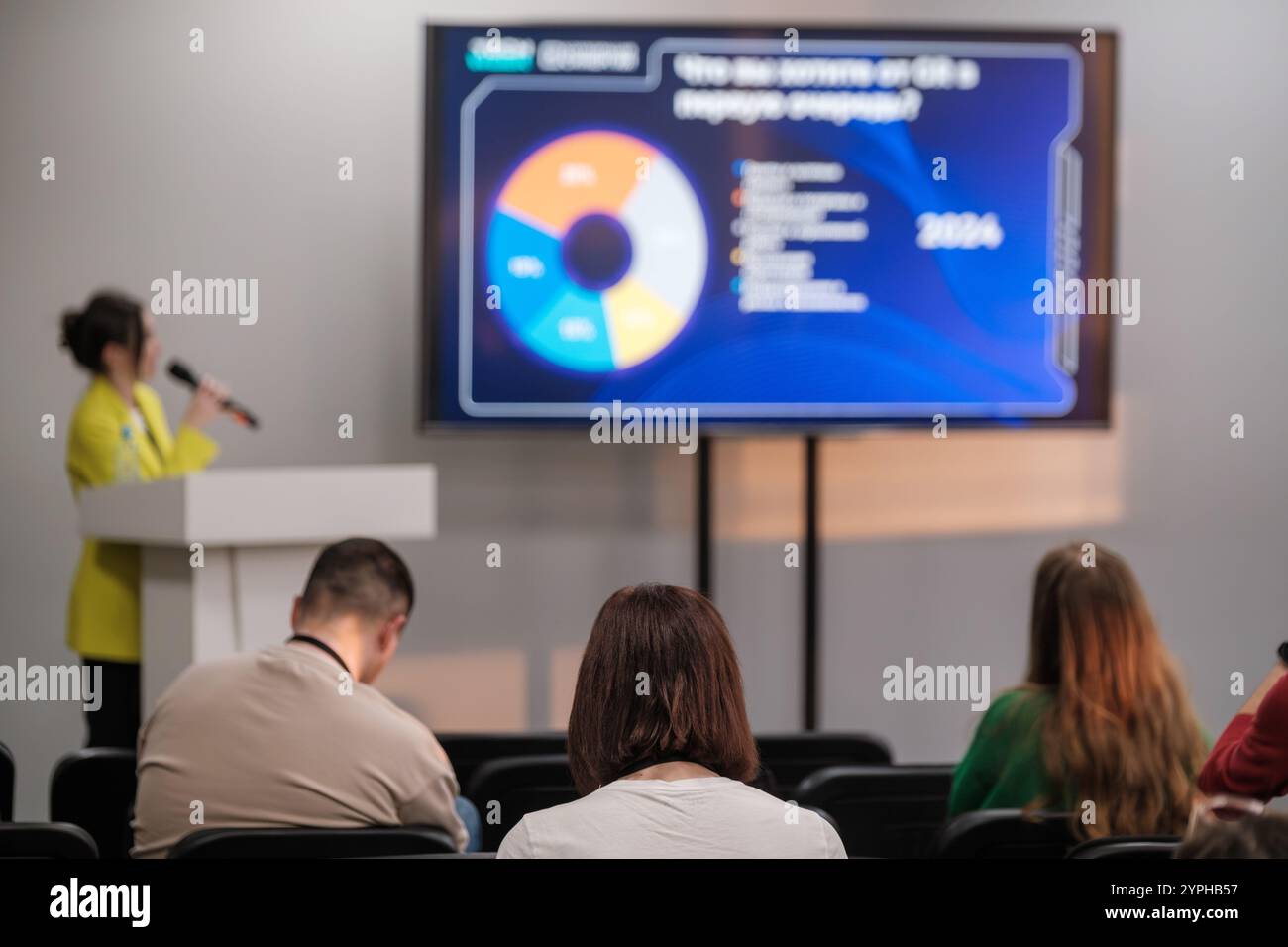 Blurred image of speaker presenting data on screen to engaged audience ...