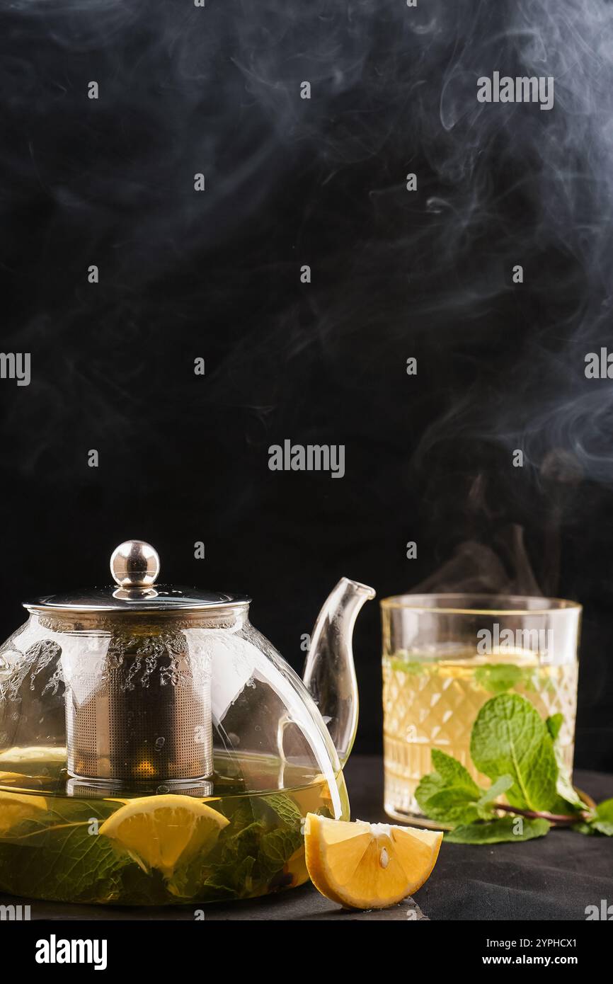 In a teapot with brown rum, cola, mint and lemon on a dark background ...