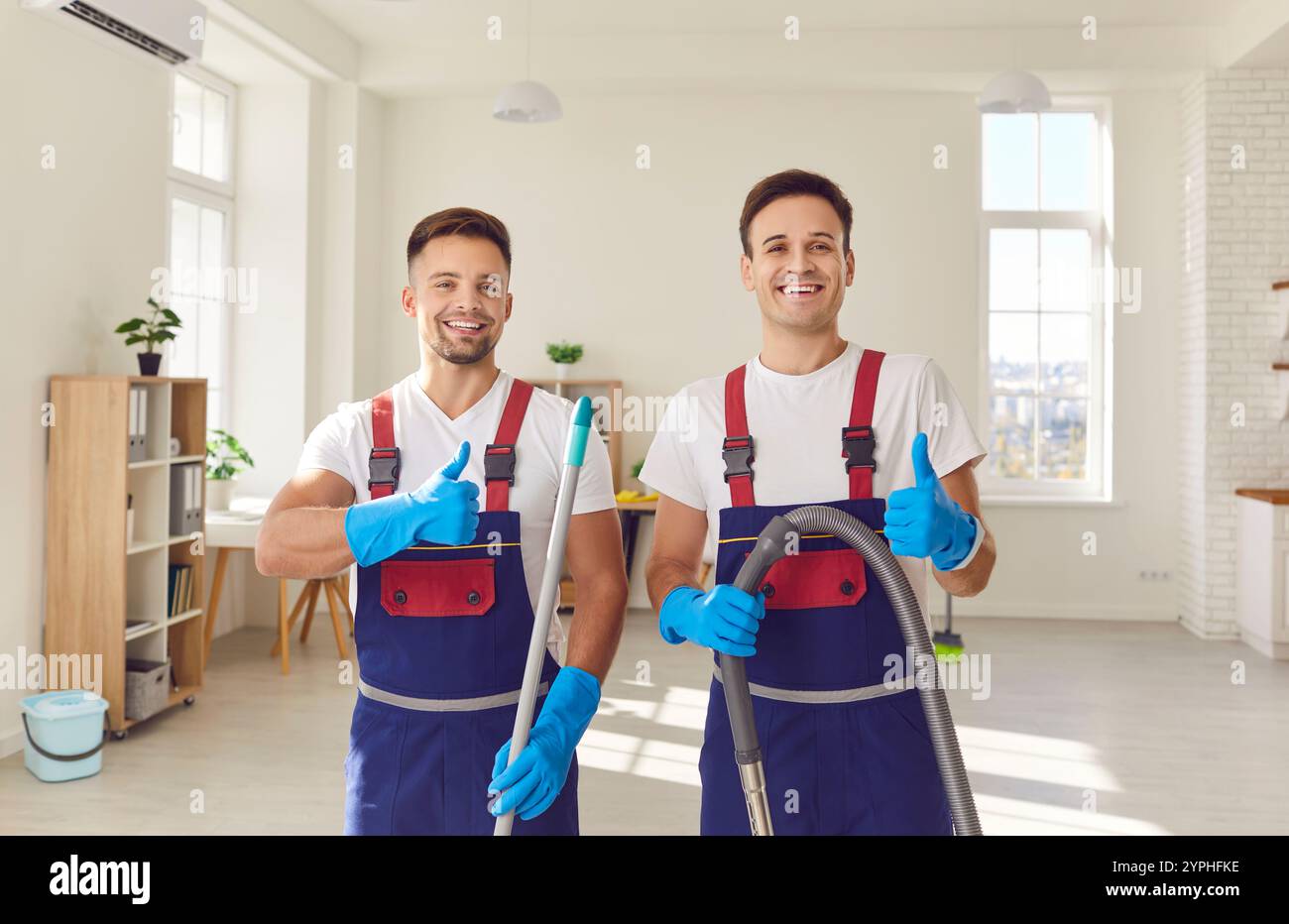 Happy janitors in uniform from professional cleaning service looking at ...