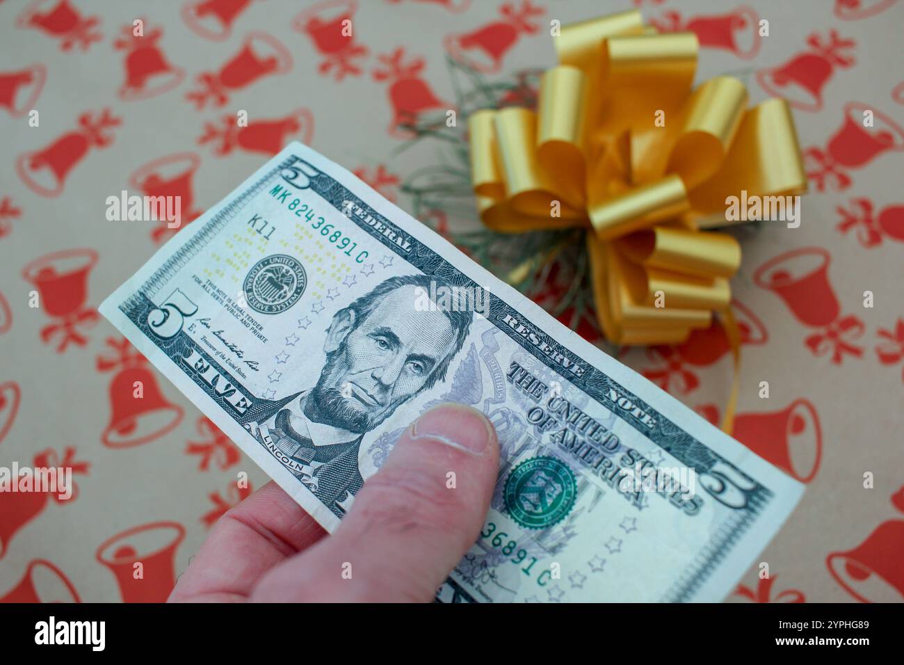 five dollar bill in my hand and a Christmas present. Concept, how much ...