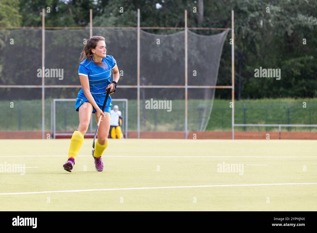 Female athlete in blue uniform running along the pitch during field ...