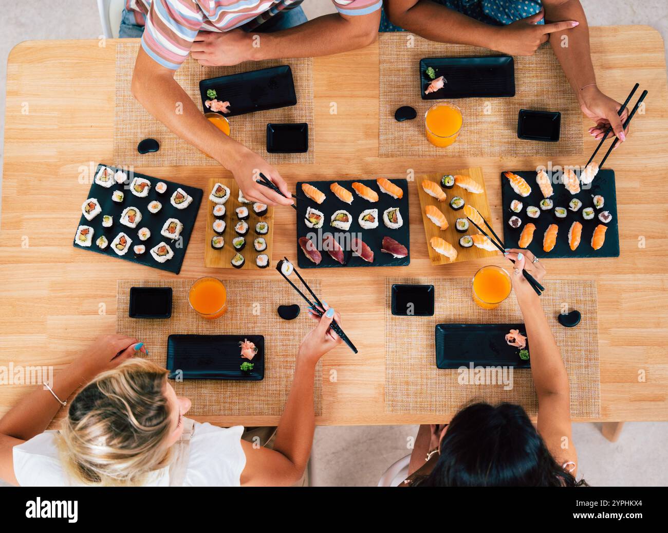 Multiethnic group of young friends meeting at home and eating sushi ...