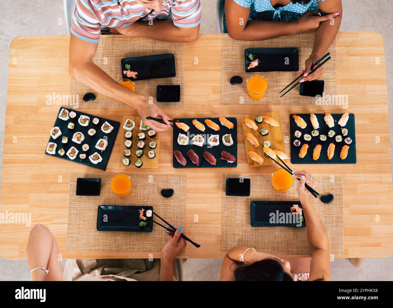Multiethnic group of young friends meeting at home and eating sushi ...