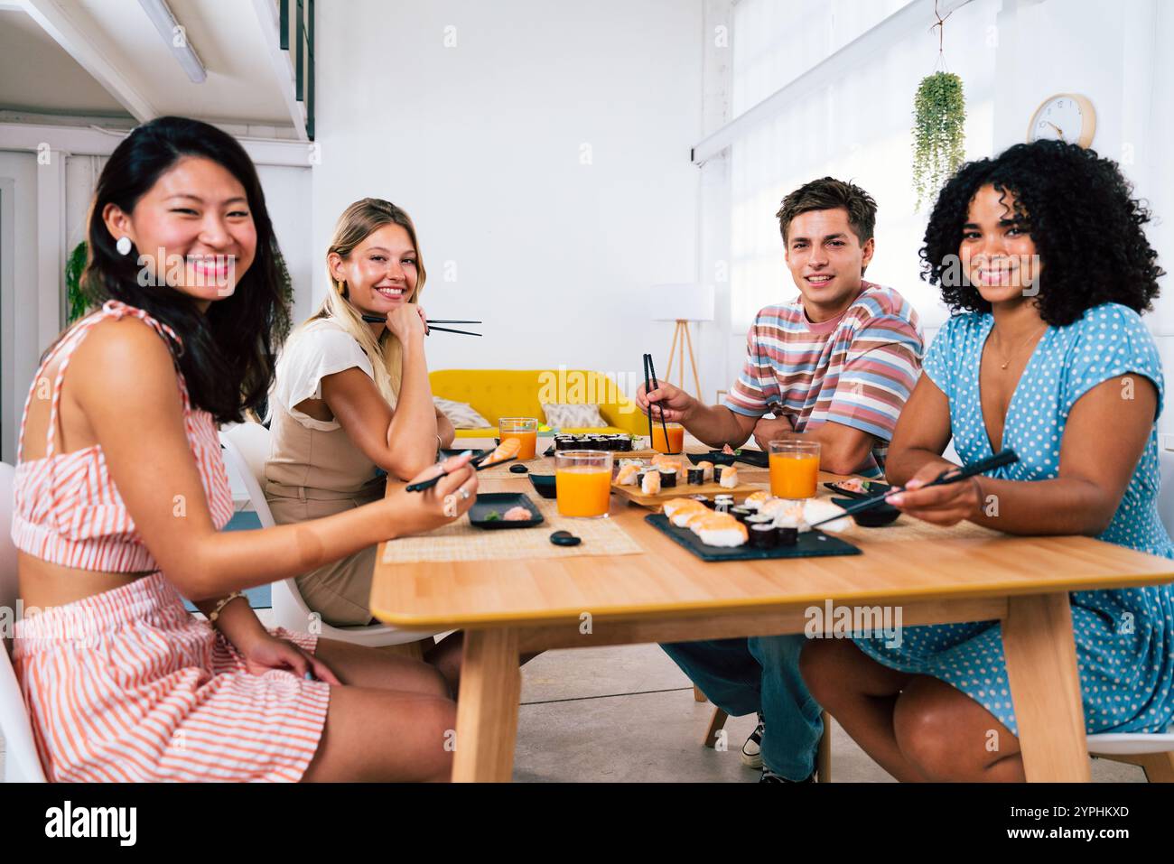 Multiethnic group of young friends meeting at home and eating sushi ...