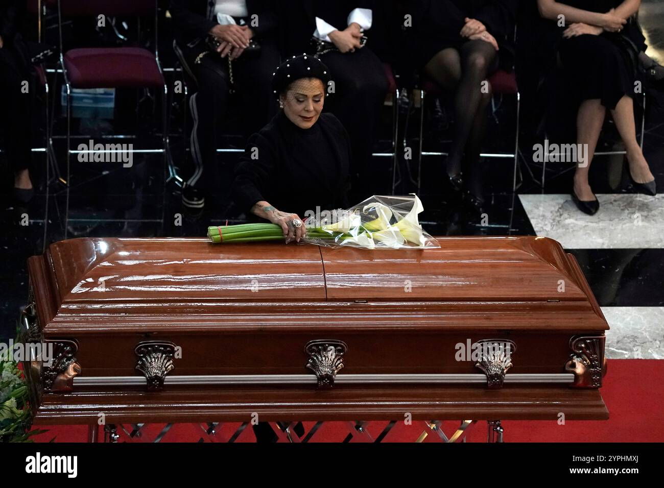 Alejandra Guzmán places a bouquet of calla lilies on the coffin that ...