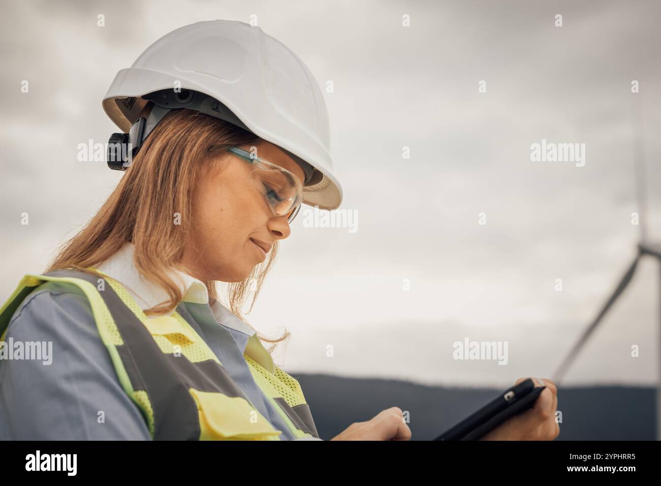 A skilled female engineer monitors wind turbines for efficiency and ...